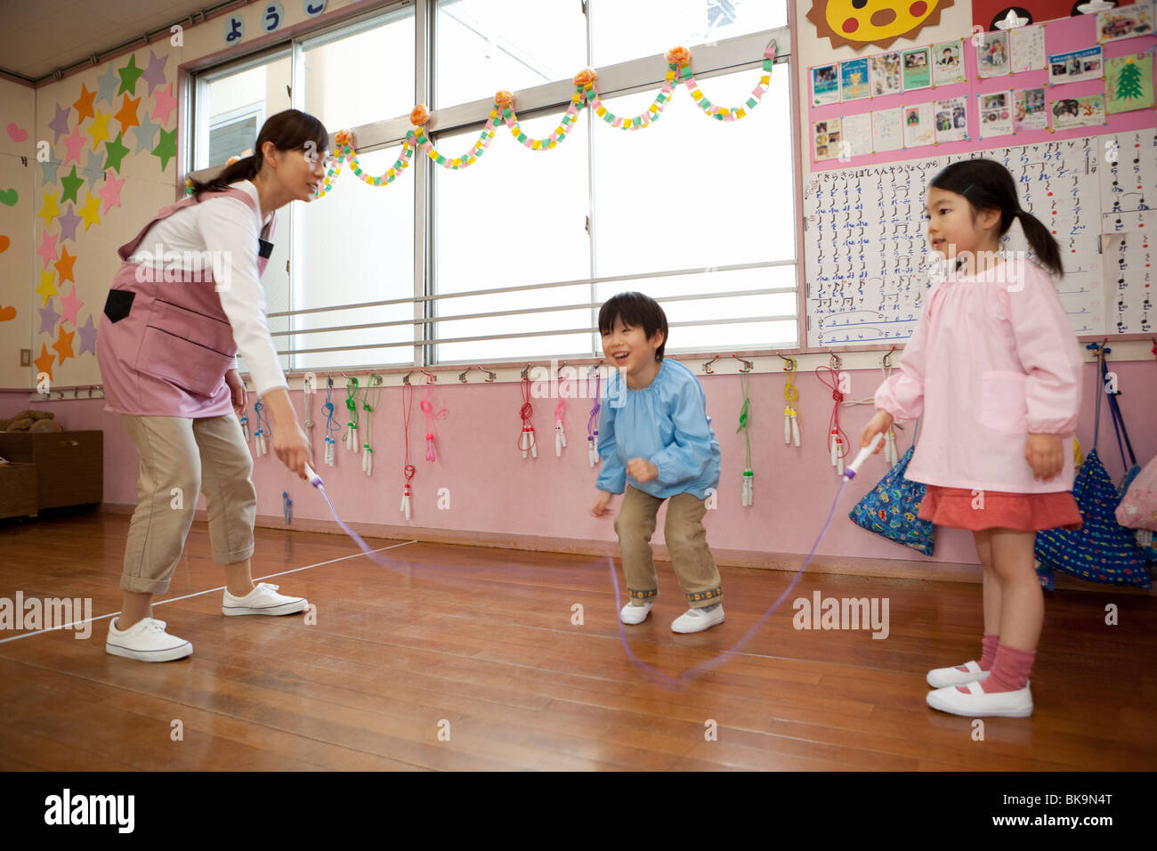 Kindergarten Teacher and Children Playing Rope Jumping Stock Photo - Alamy