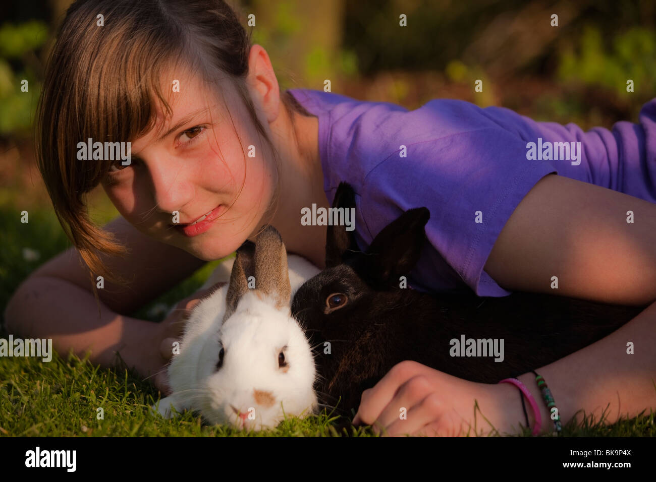 Young girl playing with two rabbits in a meadow Stock Photo - Alamy
