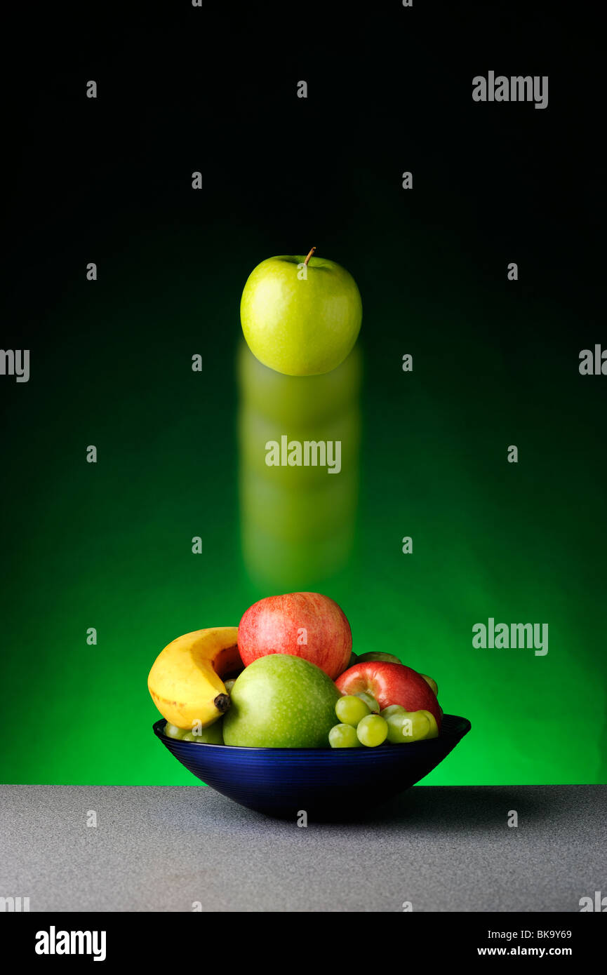 Apple rising from fruit bowl Stock Photo - Alamy
