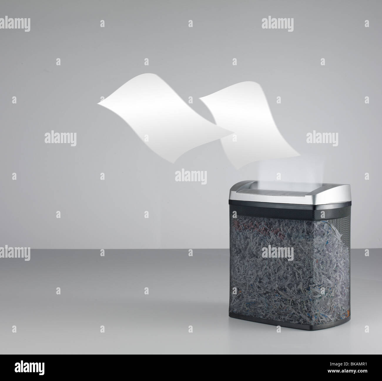 Paper shredder surrounded by flying paper sheets on a grey background ...