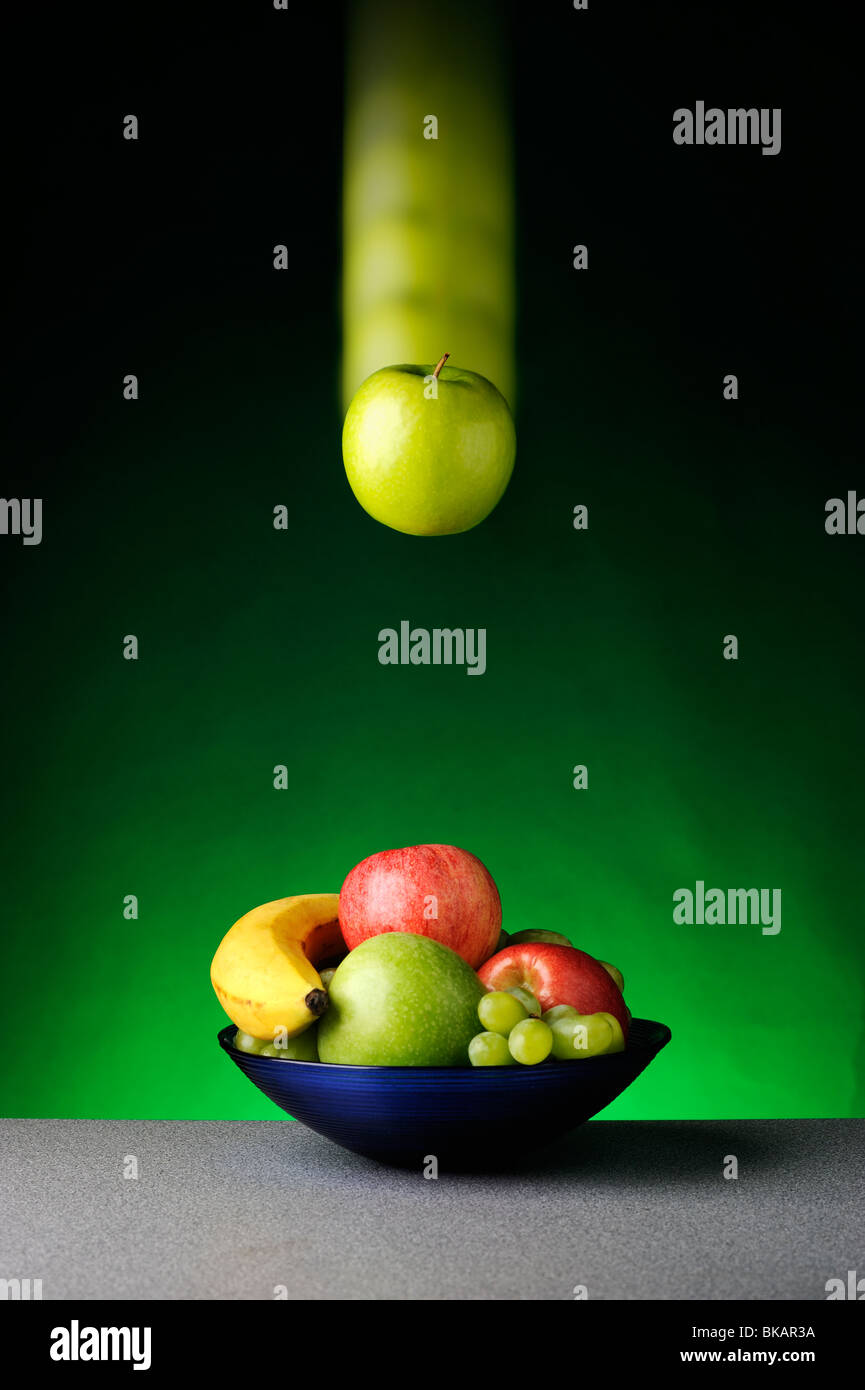 Apple falling into fruit bowl Stock Photo - Alamy