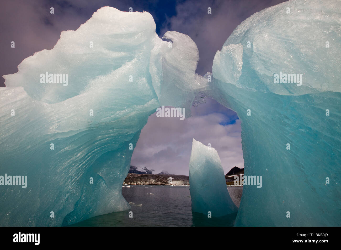 Norway Svalbard Spitsbergen Island Morning sun lights arched iceberg ...