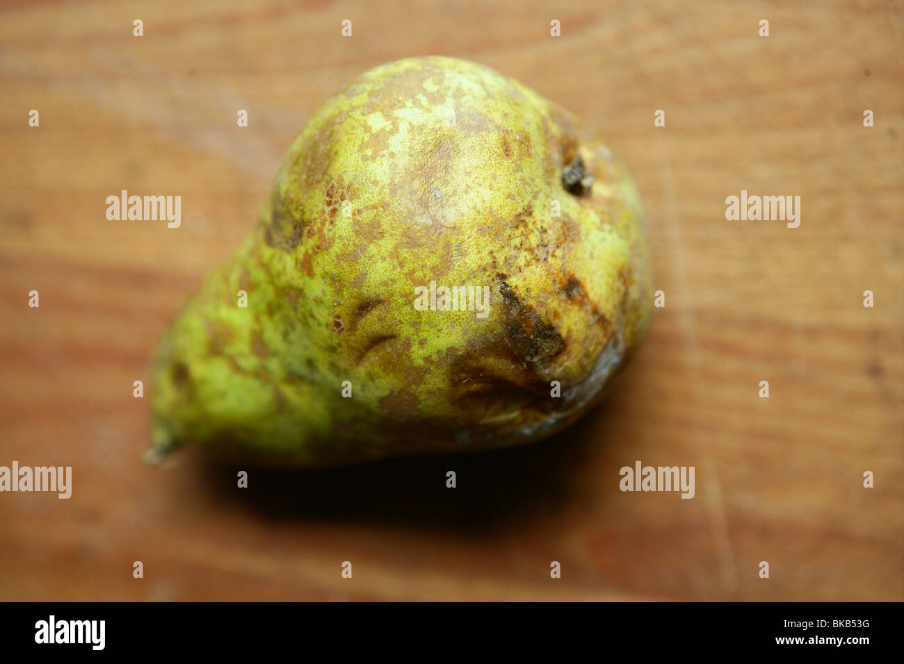 Rot green pear over warm wood table Stock Photo - Alamy