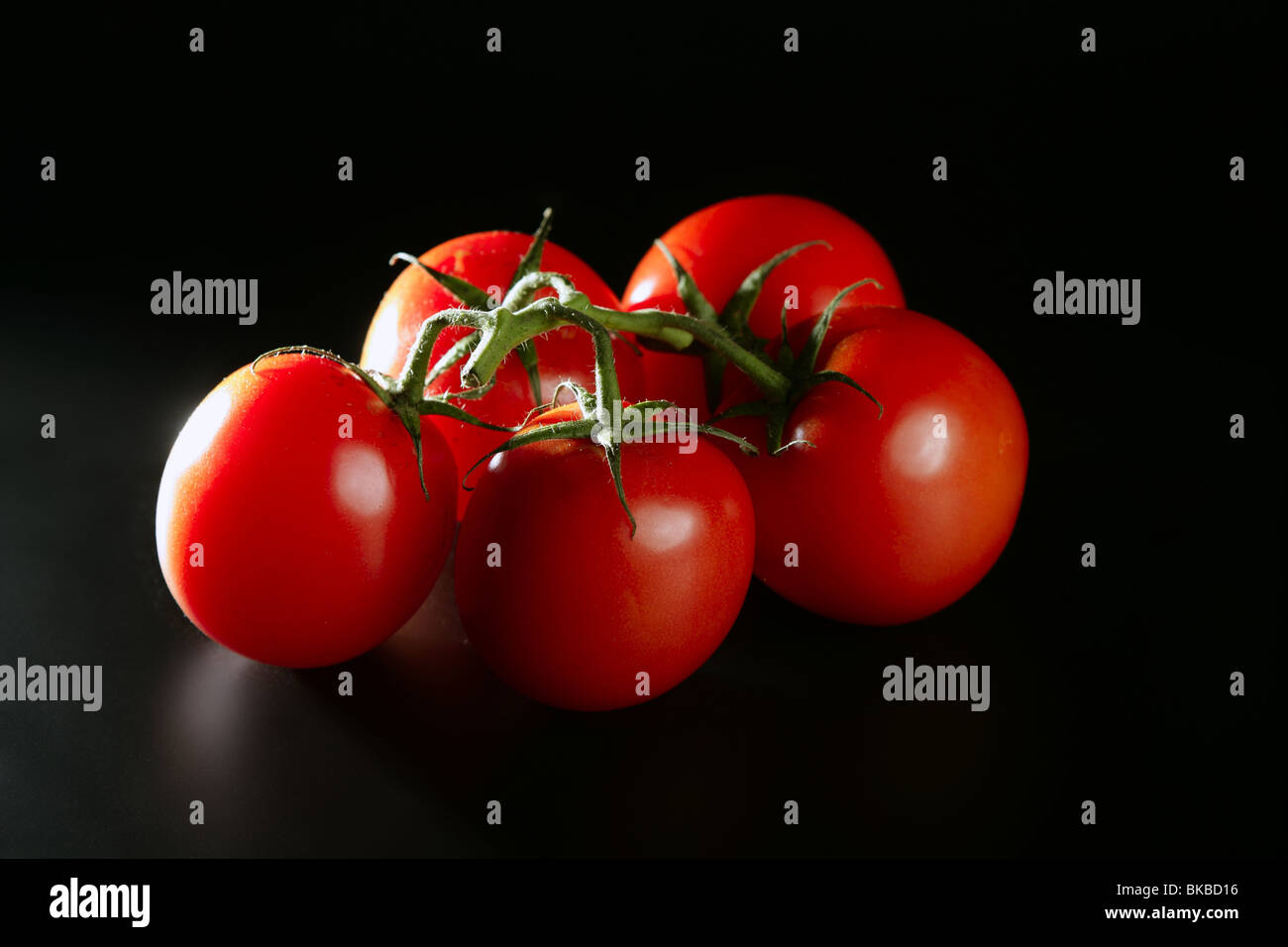 Cluster red tomato over dark black background Stock Photo - Alamy