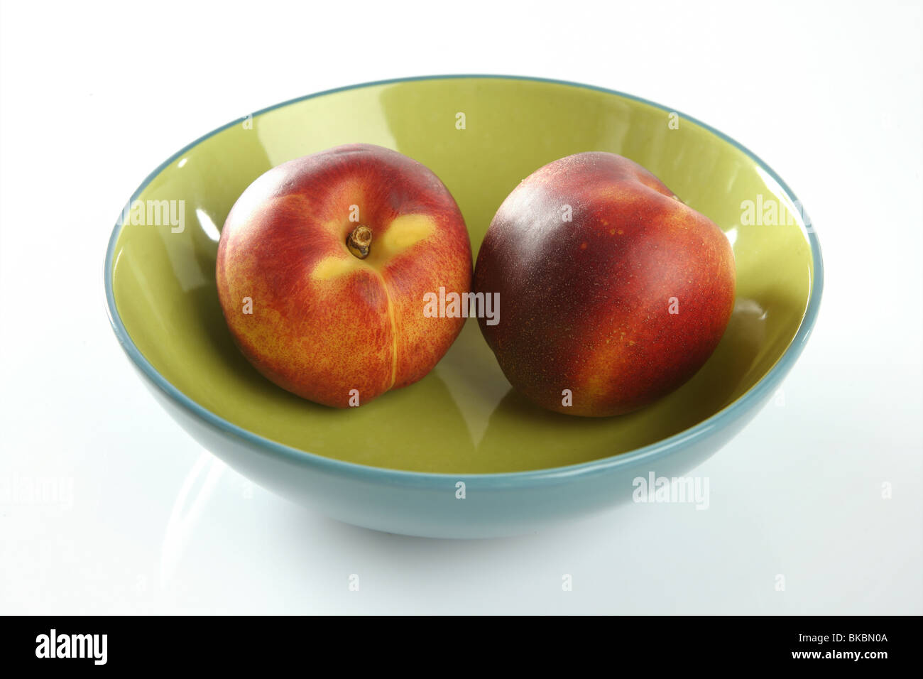 Summer fruits, two red peaches in a green dish Stock Photo - Alamy