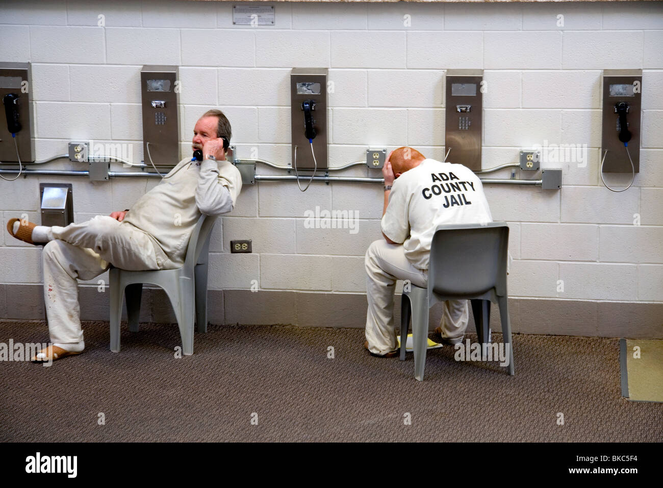 Inmates talk on telephones in the day use area of a county jail Stock ...