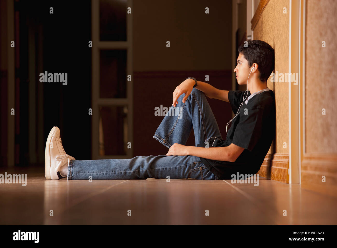 Teenage Boy Sitting On The Floor Listening To Music Stock Photo - Alamy
