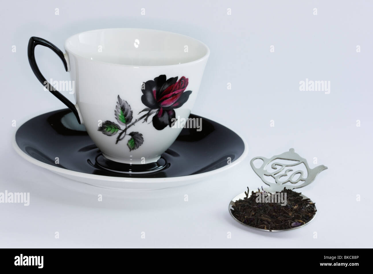 A single teacup with a flower desing and a spoon with the word tea on ...
