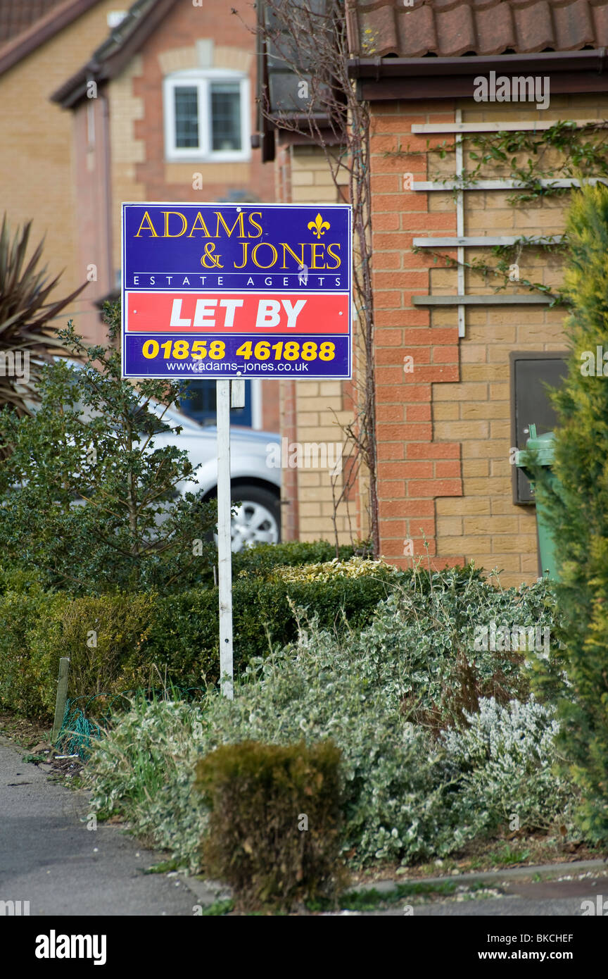 Estate Agents "let by" sign in the front garden of a house in England ...