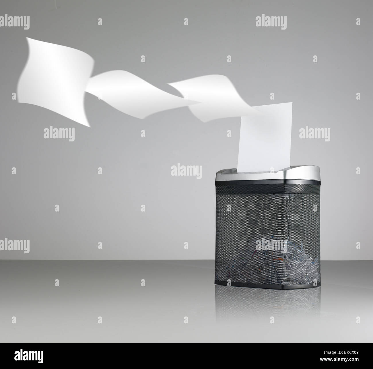 Paper shredder surrounded by flying paper sheets on a grey background ...