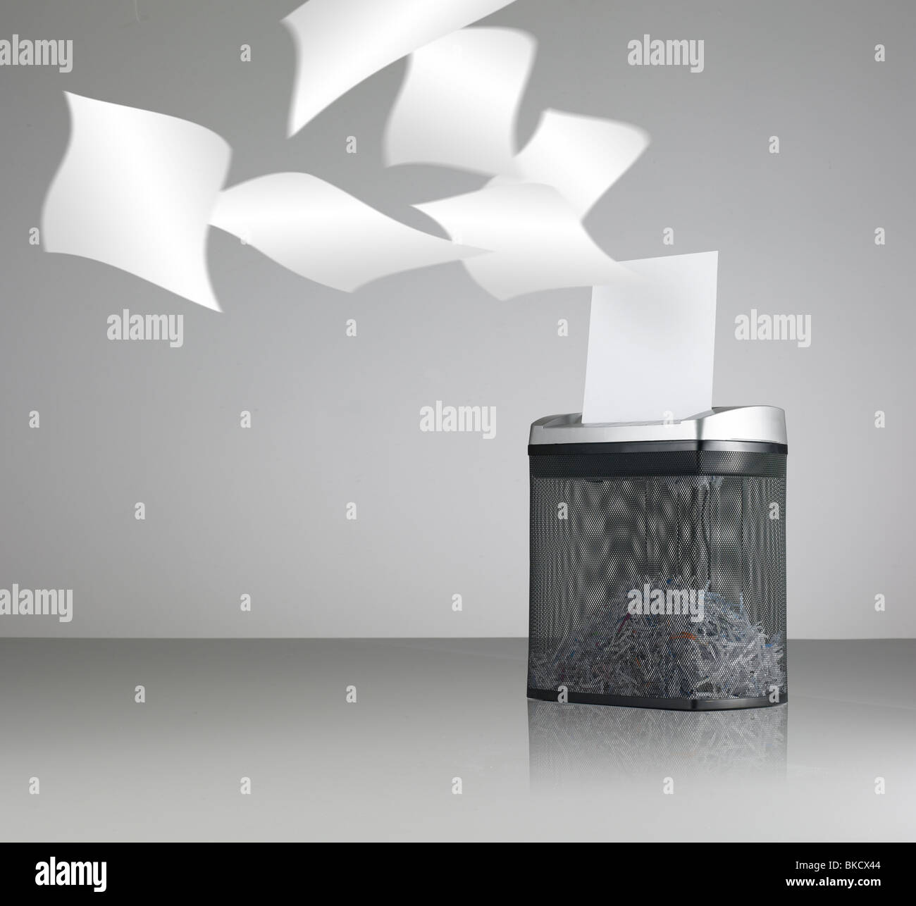 Paper shredder surrounded by flying paper sheets on a grey background ...