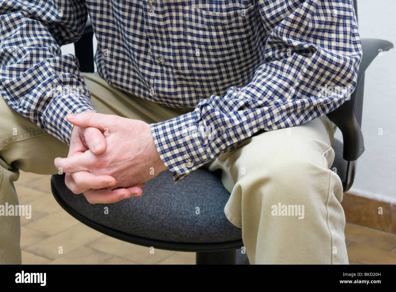man sitting on chair with his hands clasped Stock Photo - Alamy