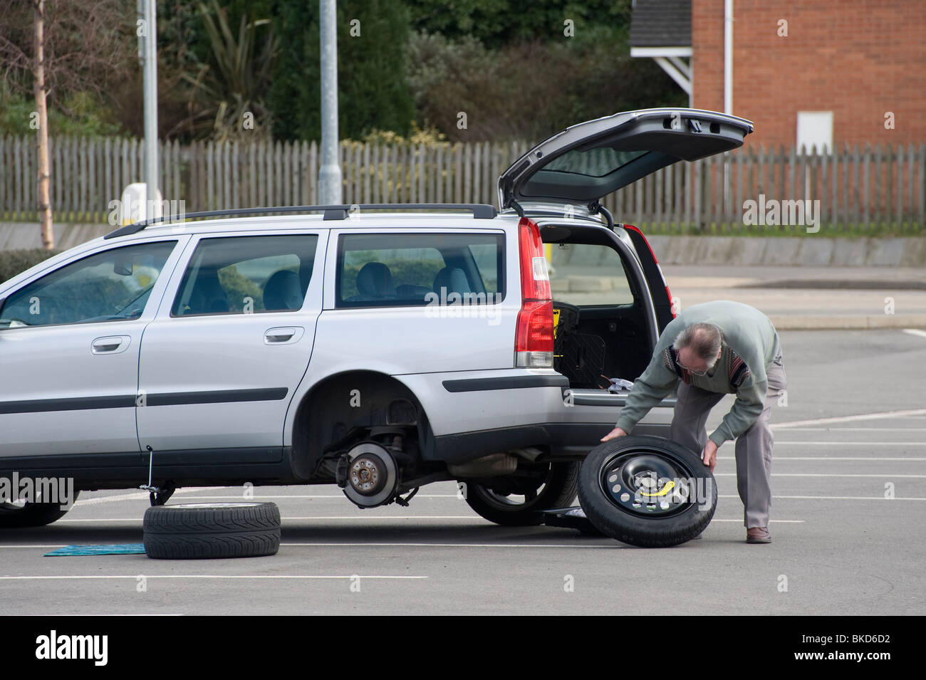 Man changing a car wheel following a puncture Stock Photo - Alamy