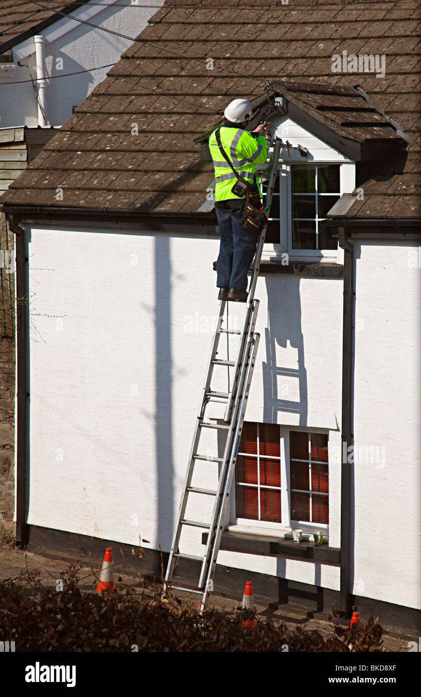 British Telecom engineer on ladder repairing phone line to house Wales ...