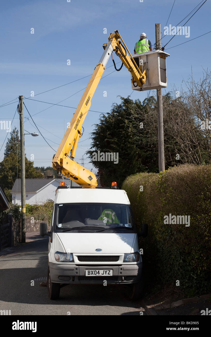 British Telecom engineer in hoist repairing phone lines on telegraph ...