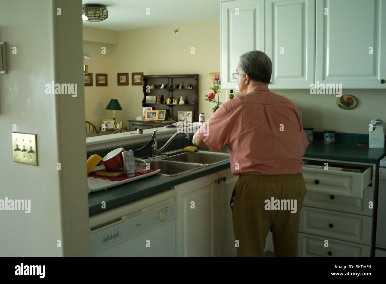 Old man cleans dishes at kitchen sink Stock Photo - Alamy
