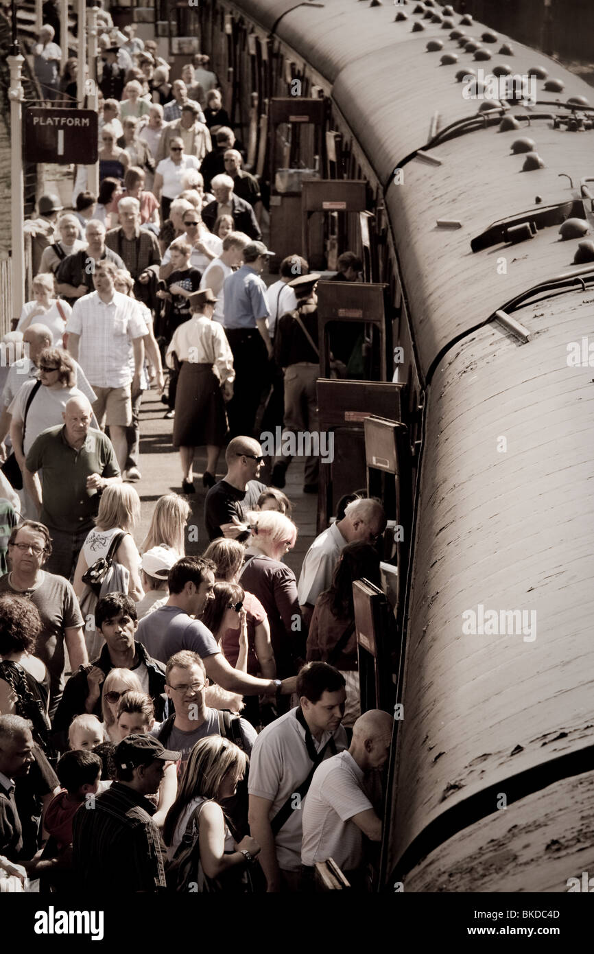 A crowd of tourists board a train on platform 1 at a station on the ...