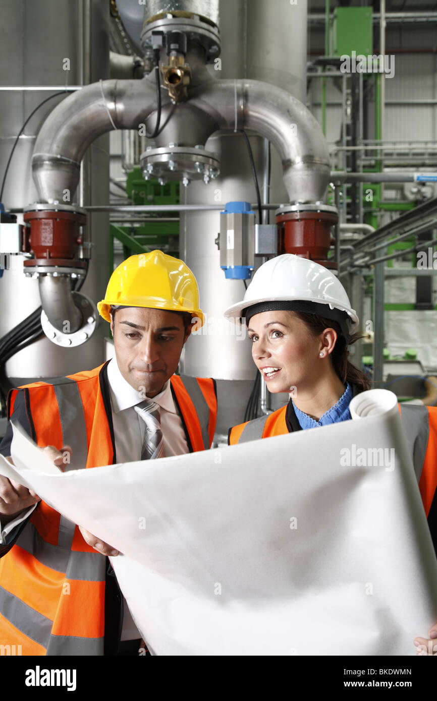 Smiling female factory manager and Asian male factory manager wearing ...