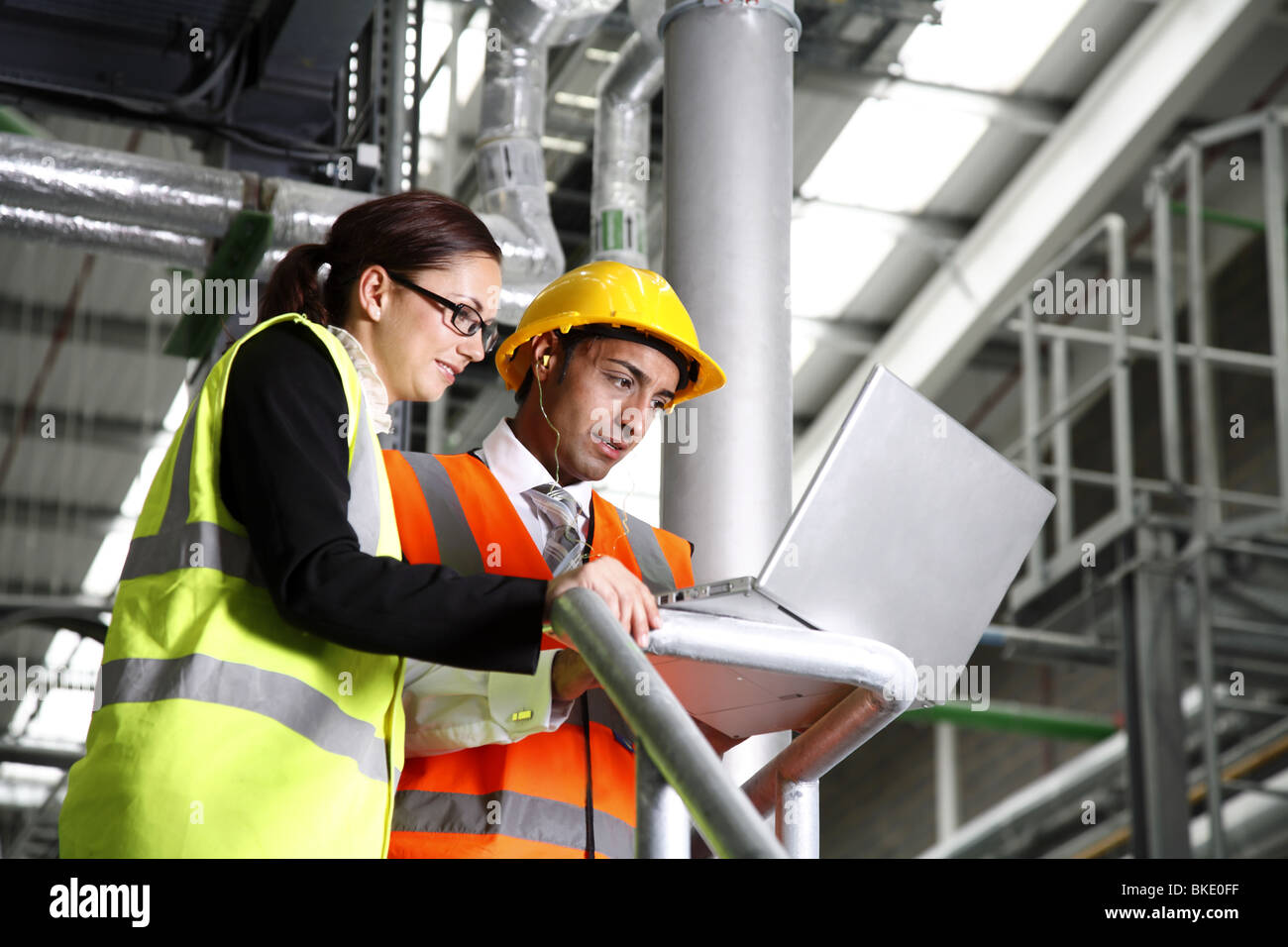 Female factory manager and asian male manager wearing safety equipment ...