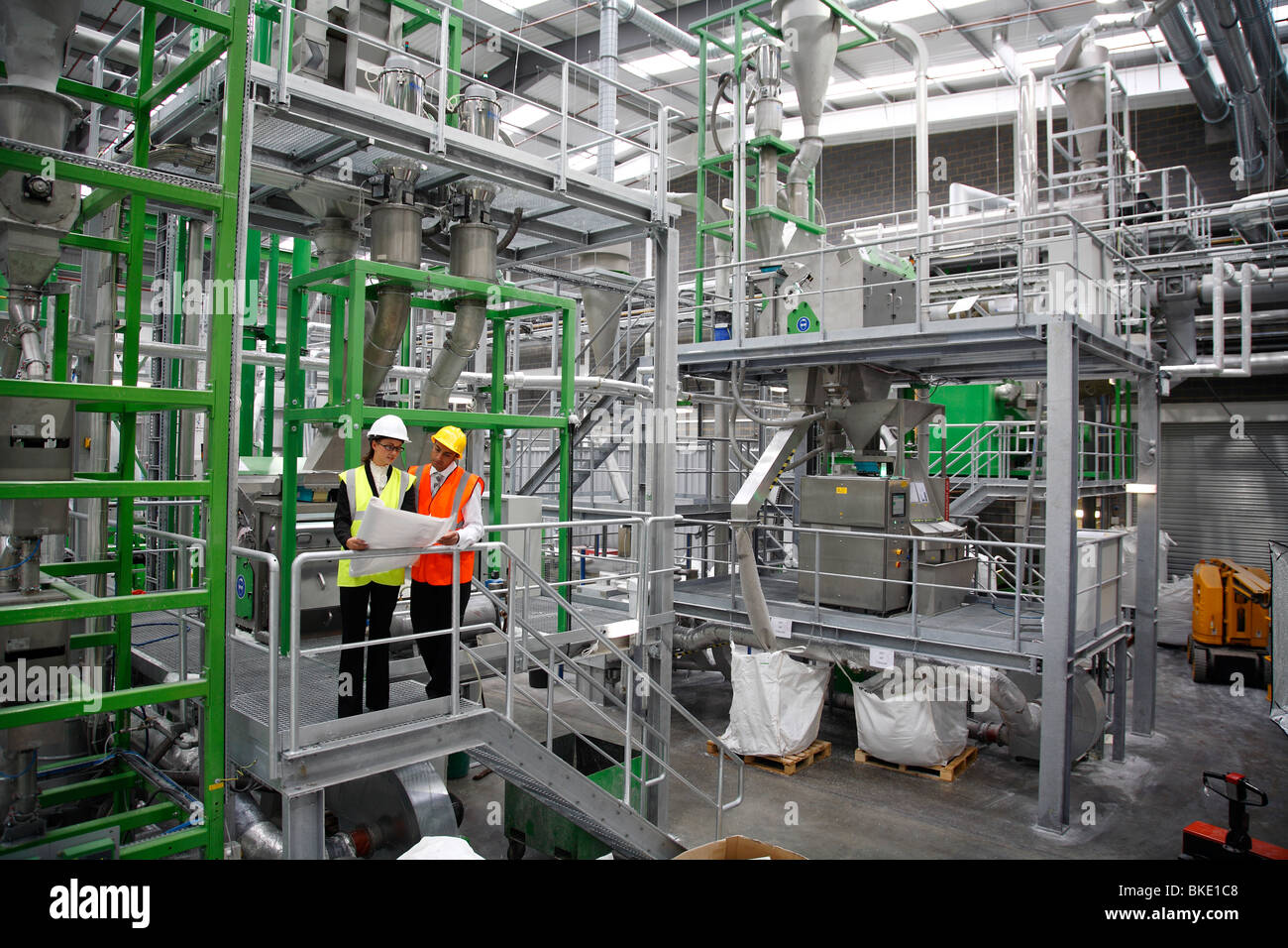 Female factory manager and asian male manager wearing safety equipment ...