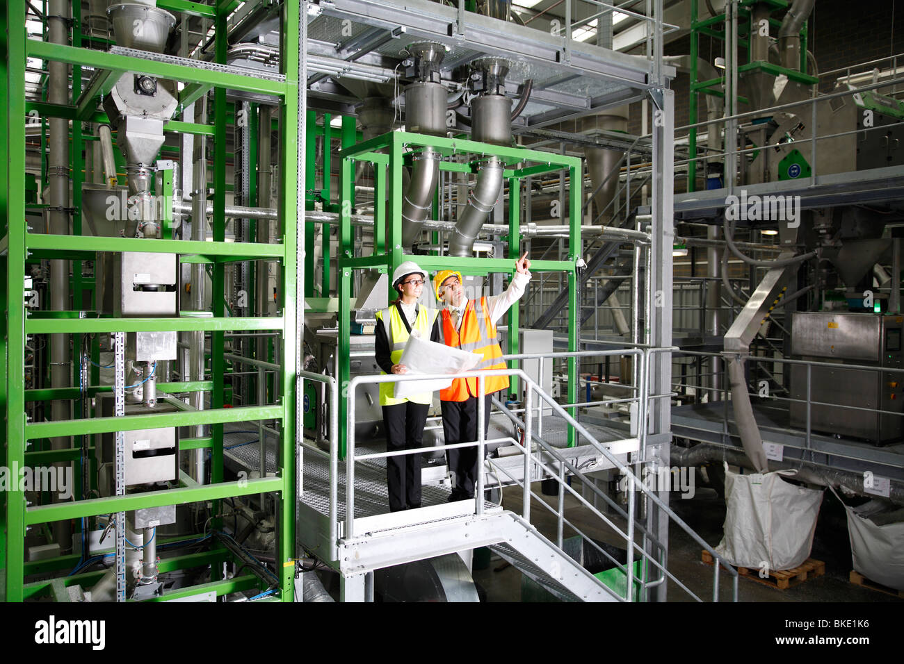Female factory manager and asian male manager wearing safety equipment ...