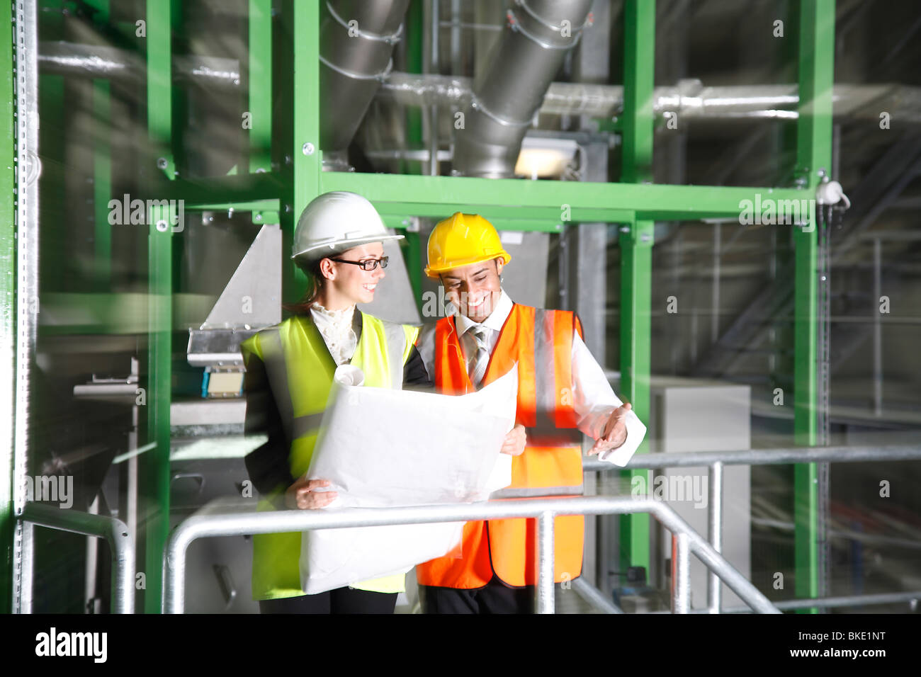 Female factory manager and asian male manager wearing safety equipment ...