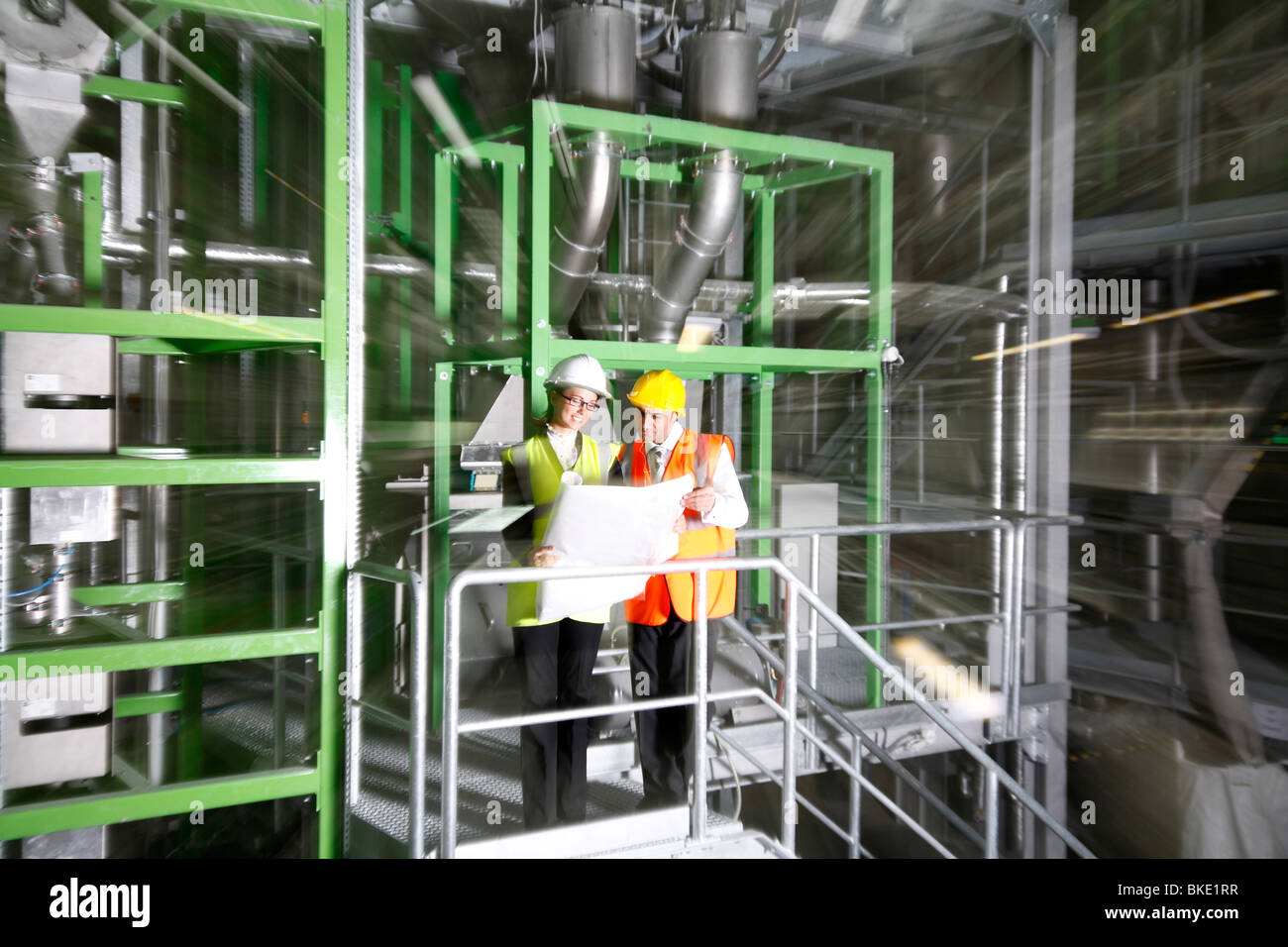 Female factory manager and asian male manager wearing safety equipment ...