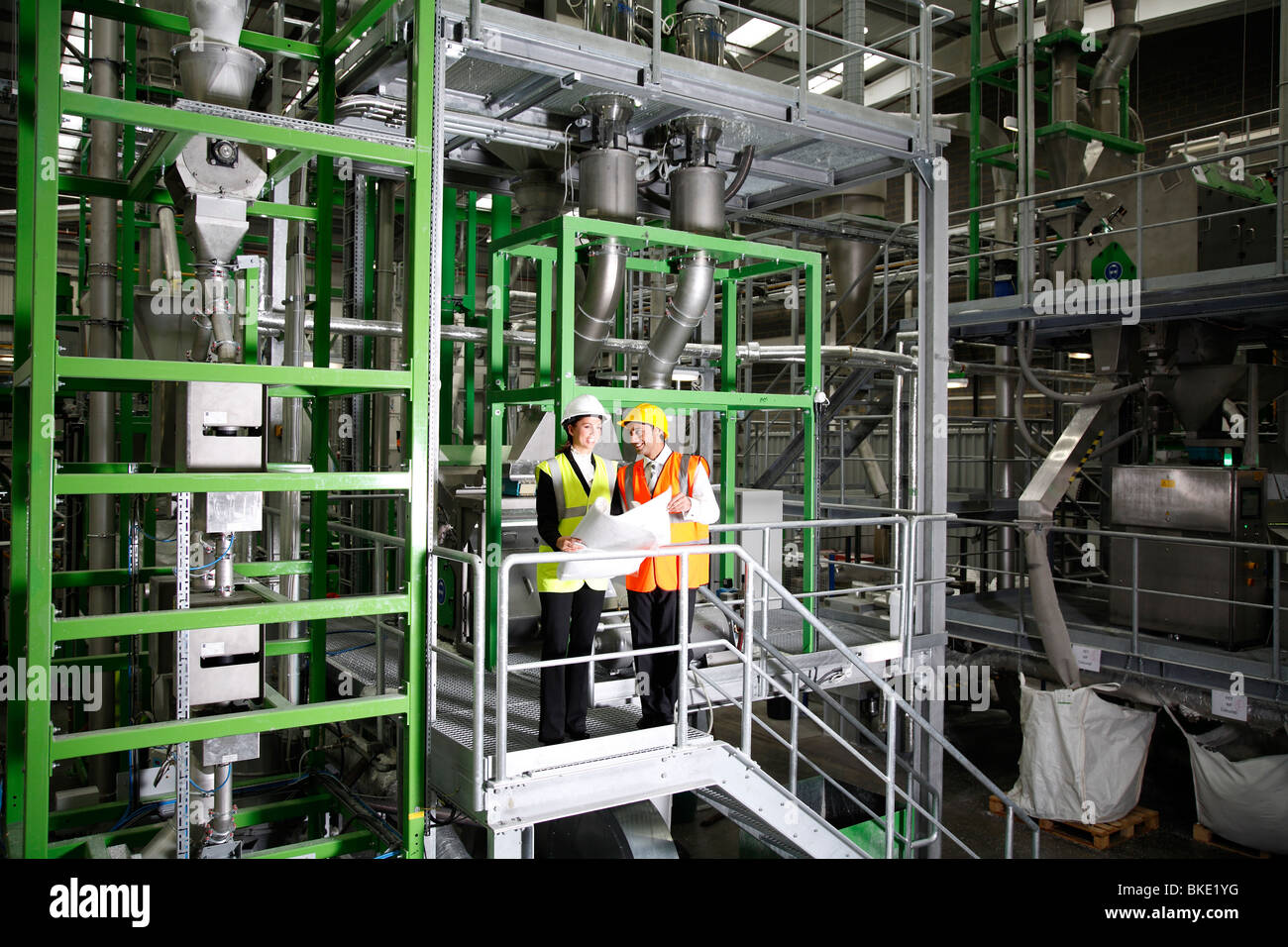 Female factory manager and asian male manager wearing safety equipment ...