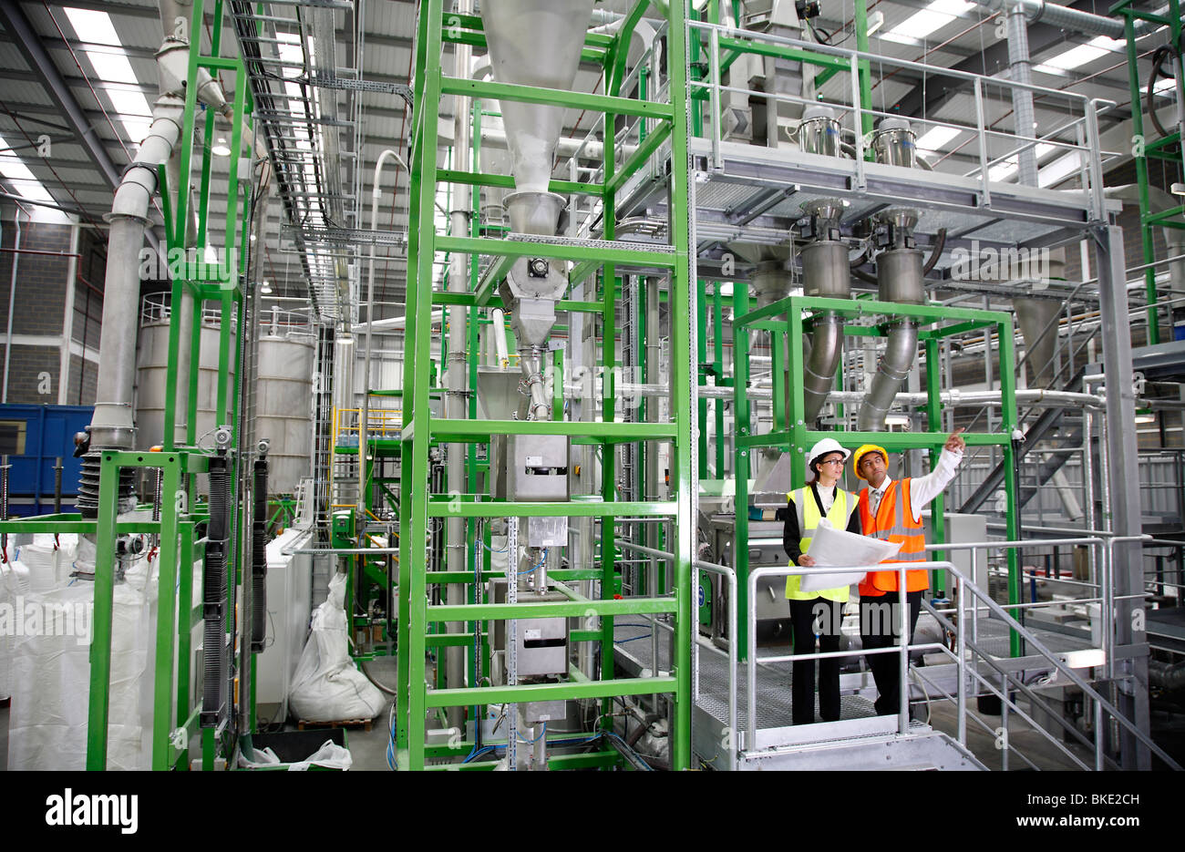 Female factory manager and asian male manager wearing safety equipment ...
