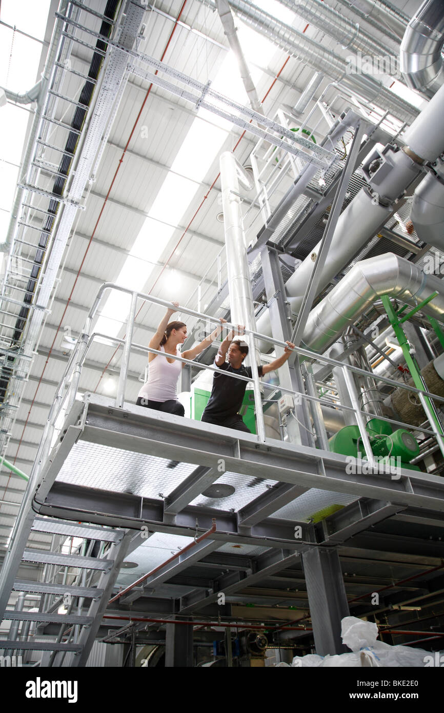 White female and Asian male in gym wear exercise in factory environment ...
