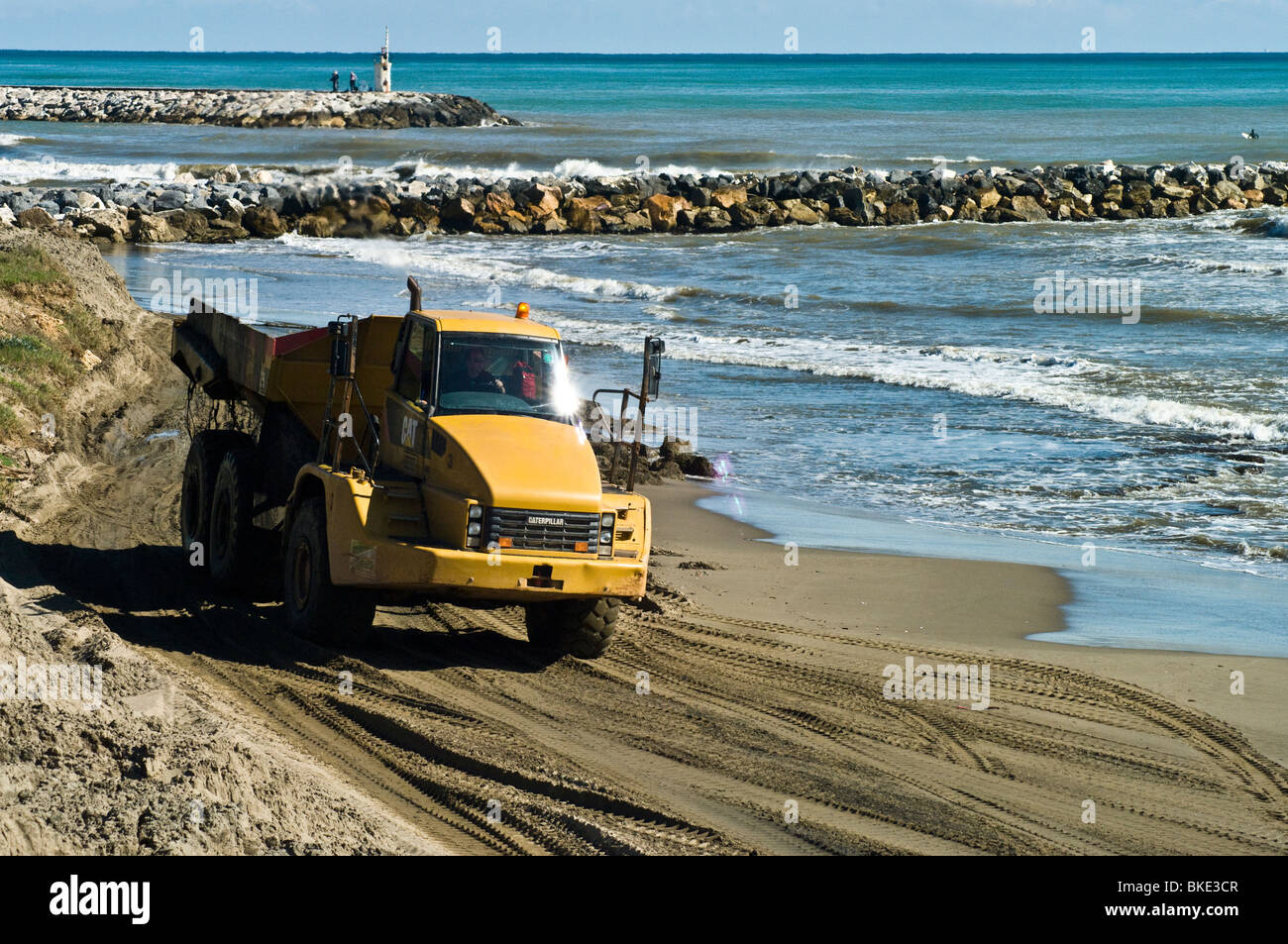Large tipper truck carrying sand along a Spanish beach in order to ...