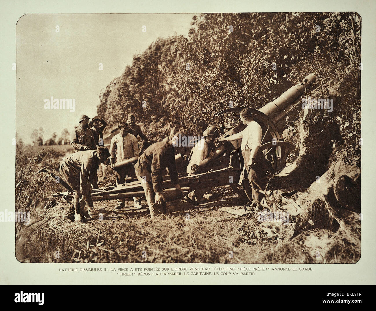 Artillery soldiers firing battery cannon from behind camouflage screen ...