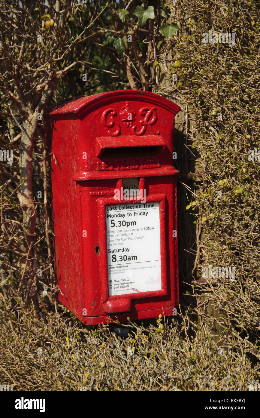 A traditional red Royal Mail post box nestled in a hedgerow at East ...