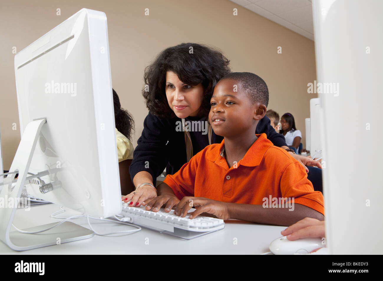 Teacher Helping Student In Computer Class Stock Photo - Alamy