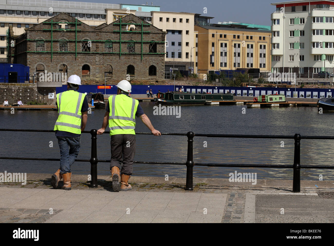 Two construction workers over looking the river at lunch break time ...