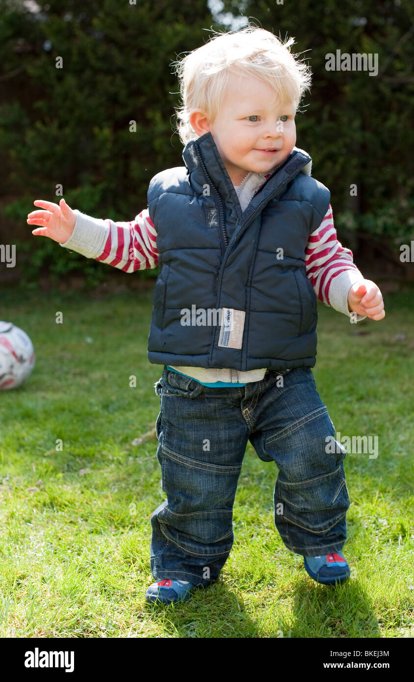 Blond Boy Toddler walking outside in garden Stock Photo - Alamy