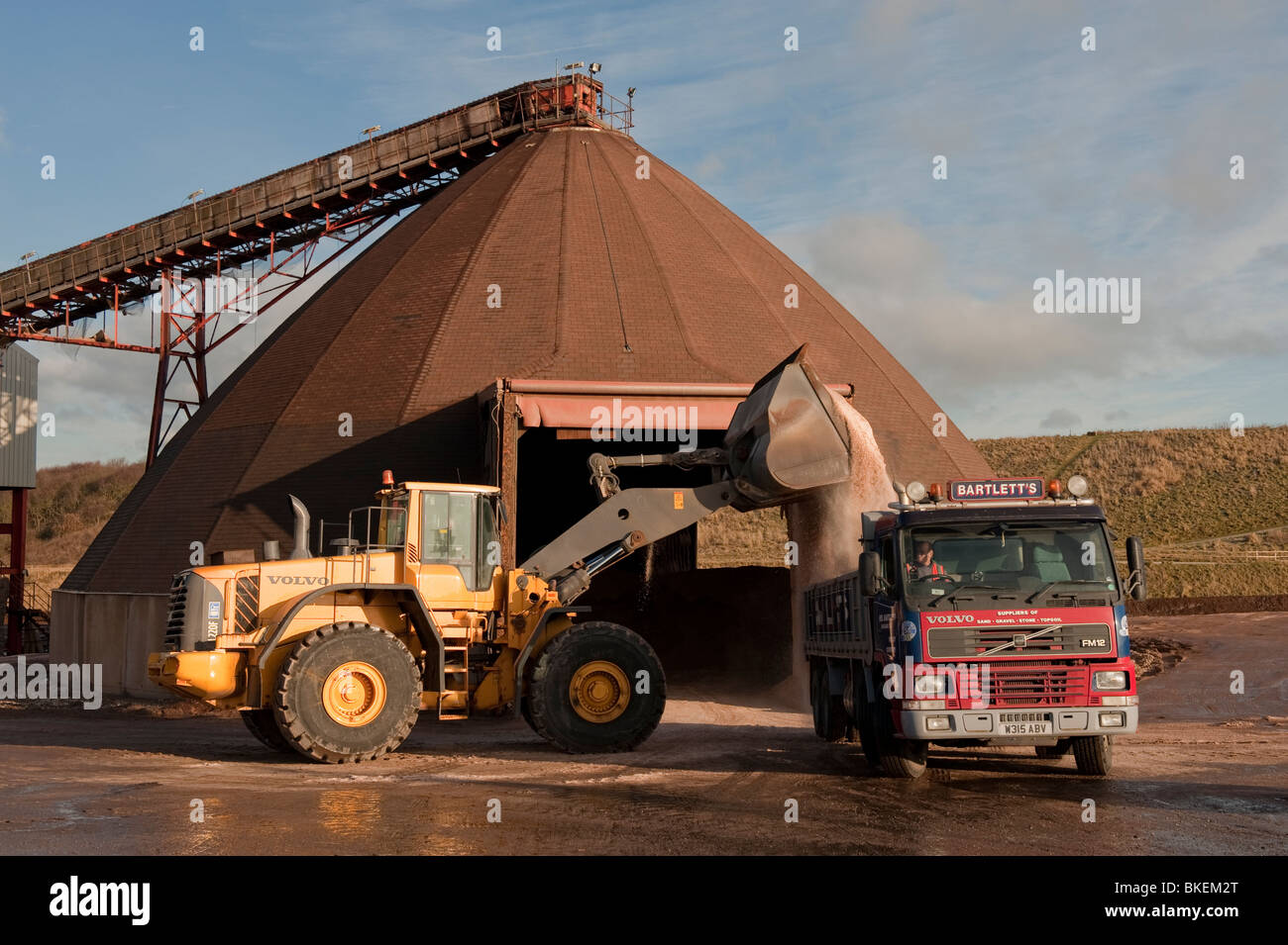 Loading road rock salt into lorry from storage building at salt mine ...