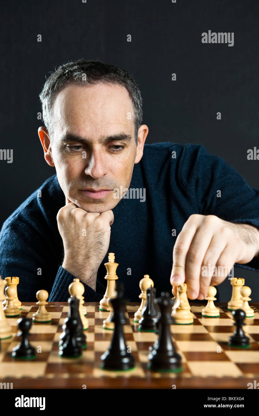 Man moving a chess piece on wooden chessboard Stock Photo - Alamy