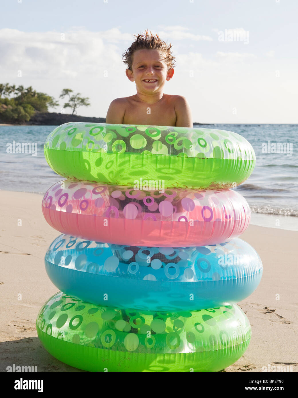 Boy surronded by stack of colorful inner tubes Stock Photo - Alamy