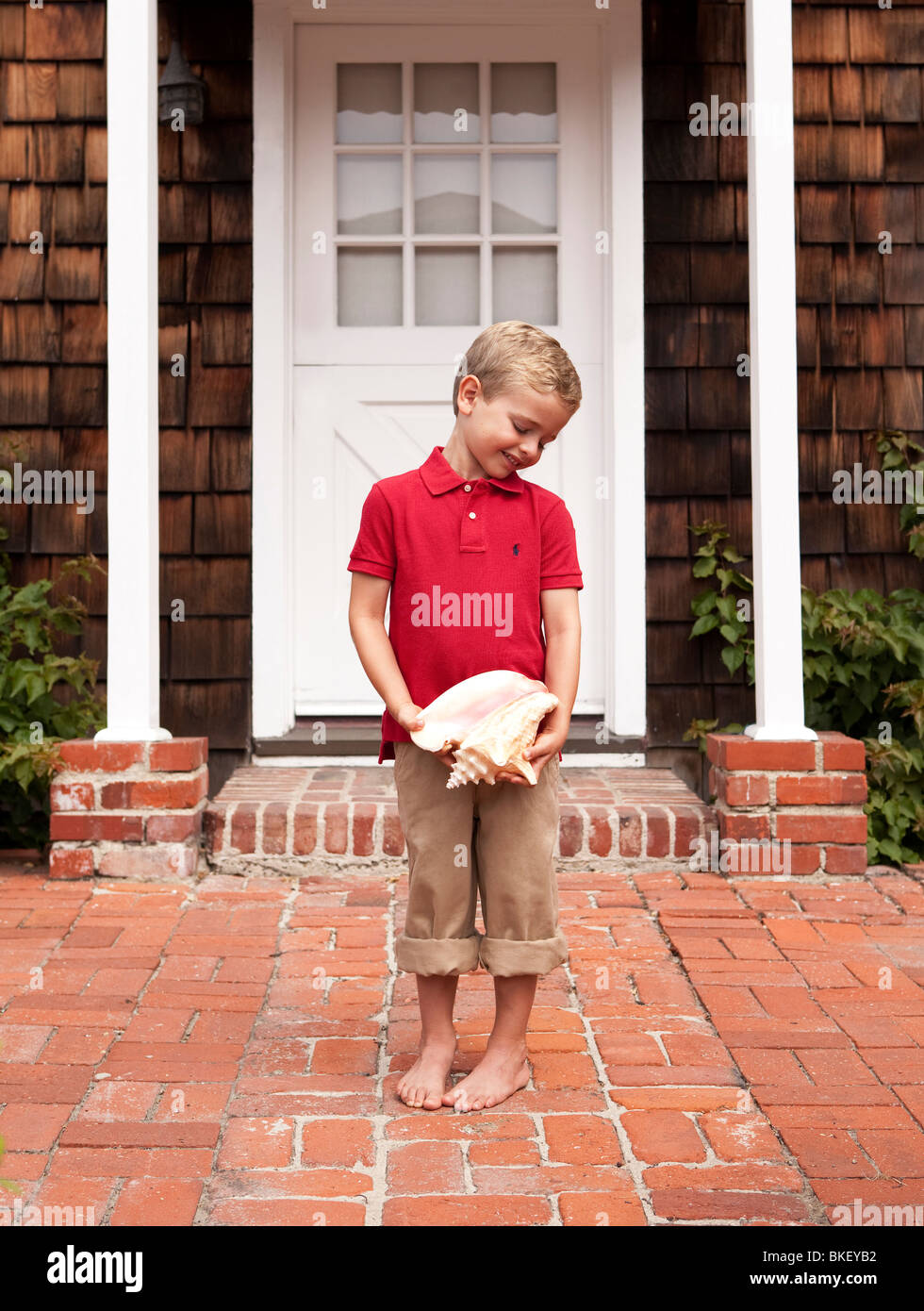 Boy on sidewalk holding seashell Stock Photo - Alamy