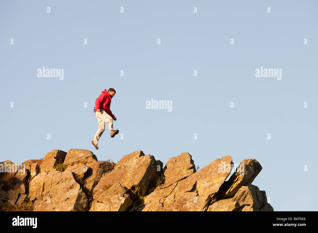 A climber jumping on a ridge above Chapel Stile in the Langdale Valley ...