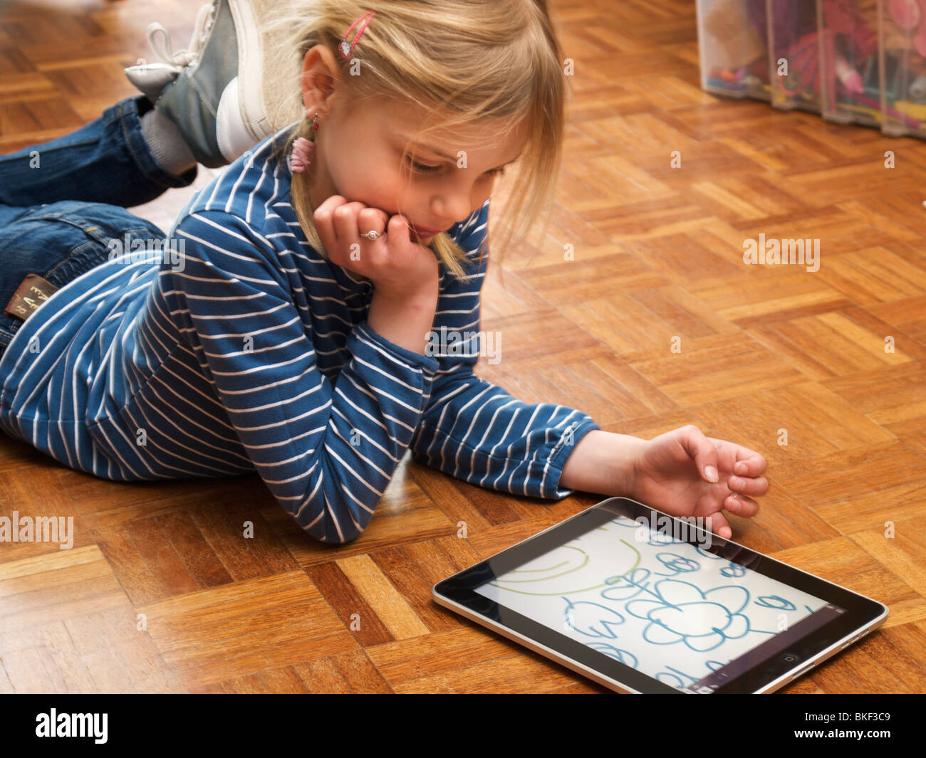 Child on living room floor playing with Apple iPad touchscreen computer ...