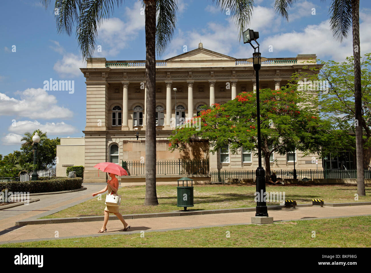 woman with umbrella at Queens Gardens in front of the old State Library ...