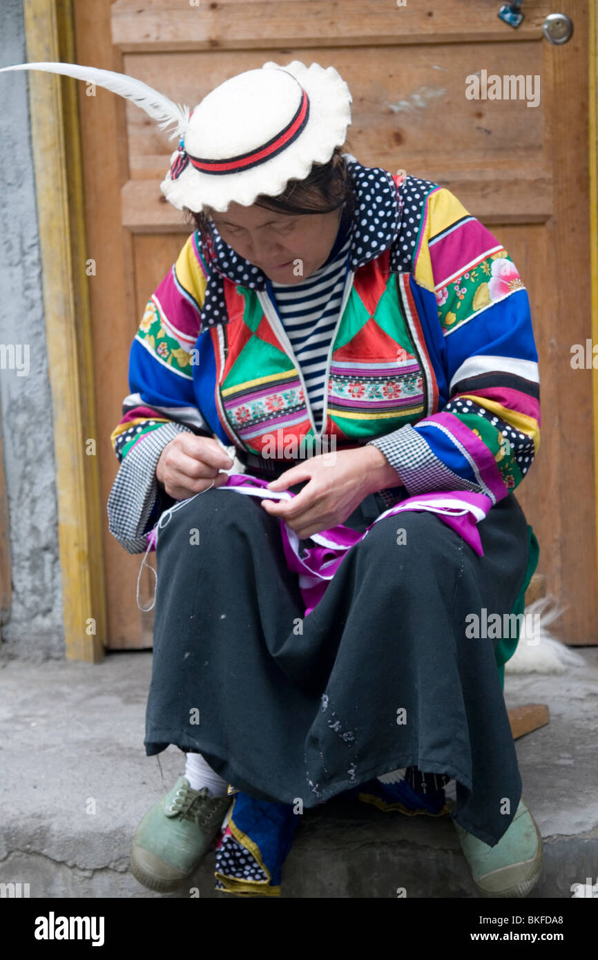 A woman of the Baima ethnic group sewing clothes manually outside her ...