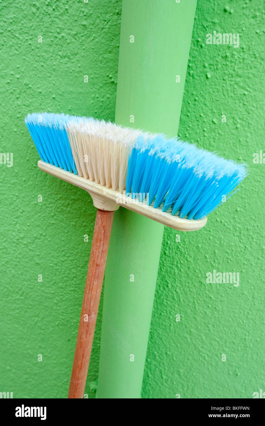 Household broom leaning against lime green wall of house in Burano ...