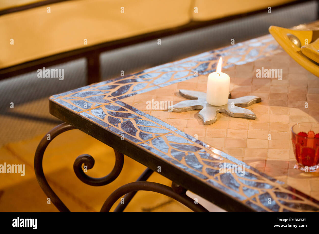 Close-up of lighted candle on metal table with tiled top Stock Photo ...