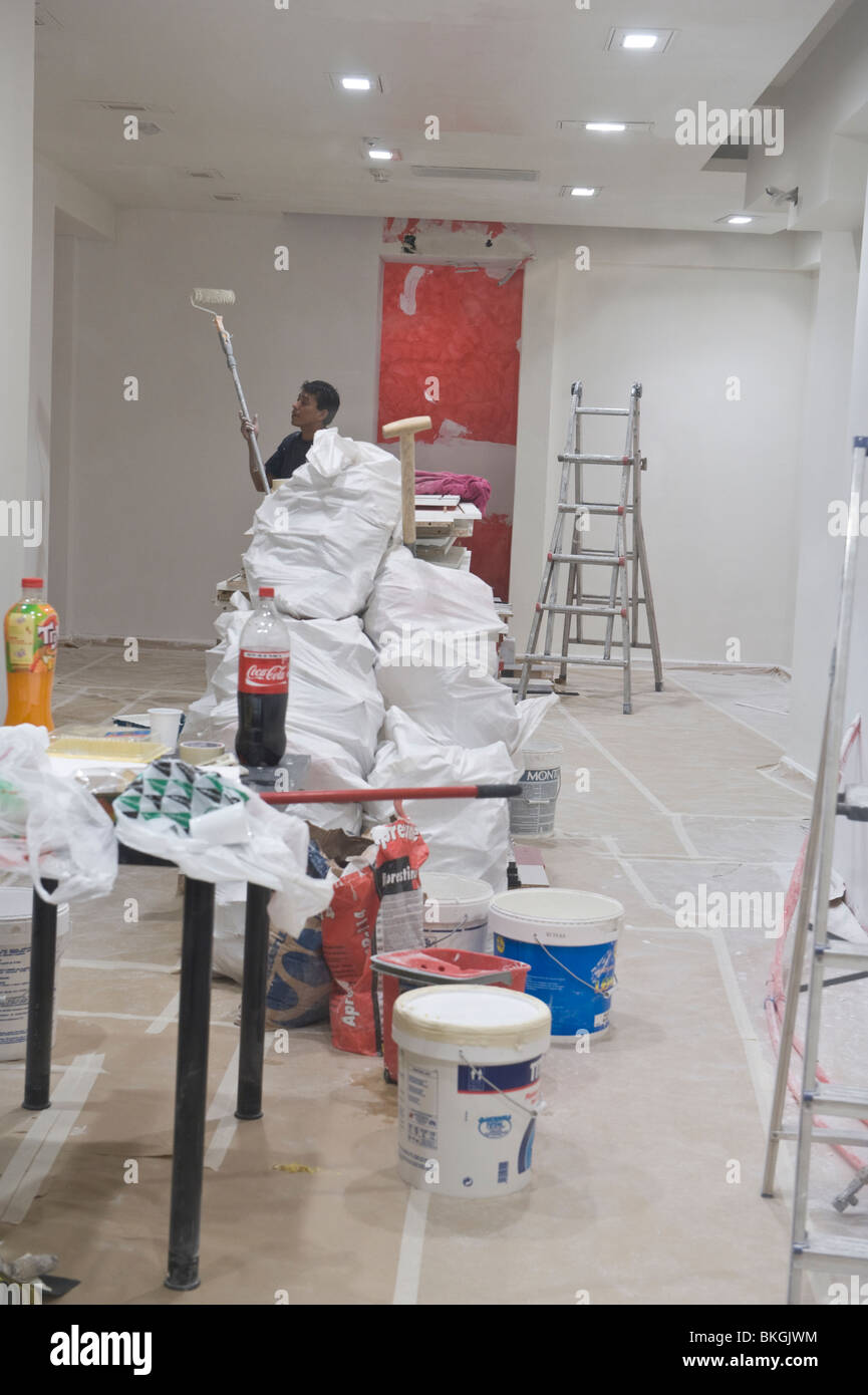 Man painting walls with white paint, some walls are red Stock Photo - Alamy