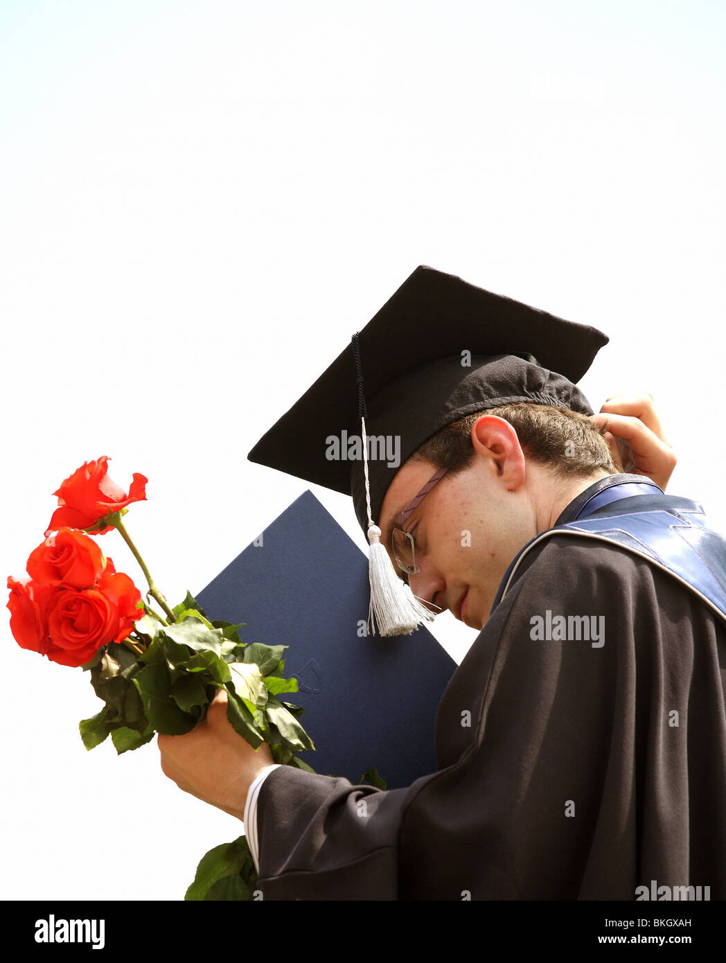 Student holding red roses after his graduation ceremony Stock Photo - Alamy