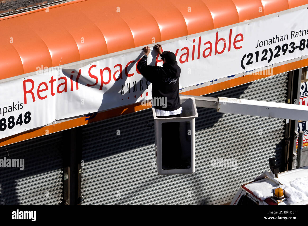 Worker attaching sign, advertising space for rent on Nostrand Avenue ...