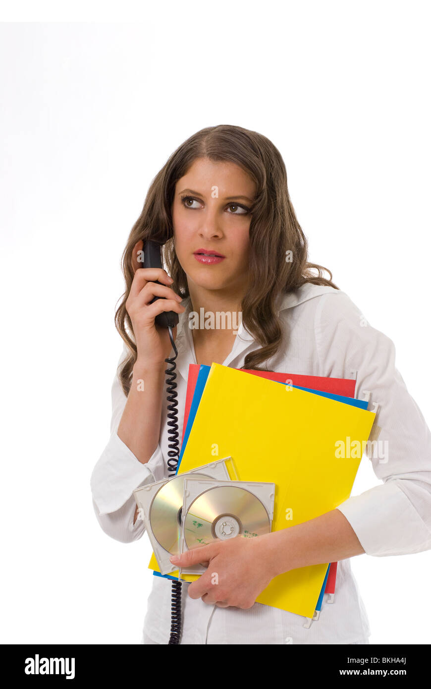 Attractive young office worker holding files and CDs while talking on ...